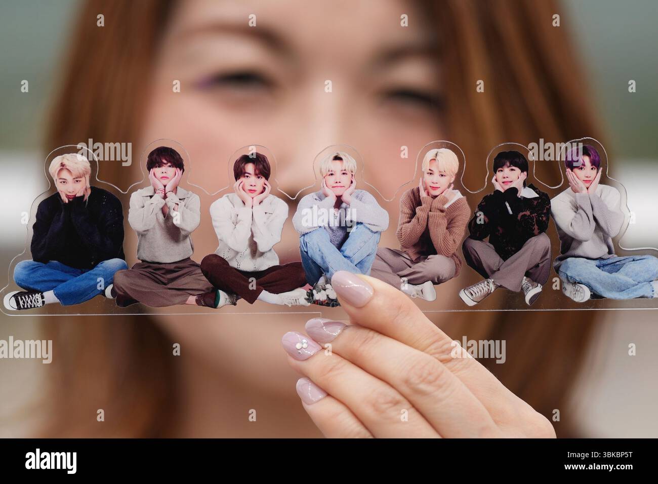 FILE - A fan of K-pop band BTS poses with a group photo of BTS during ...