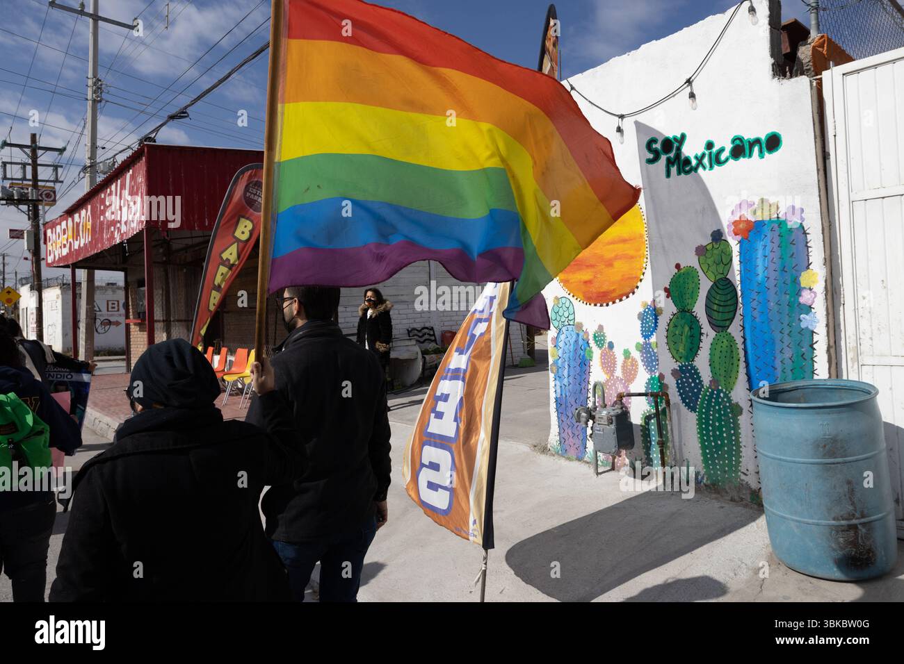 A group of people holds a rainbow pride flag during a daytime gathering ...