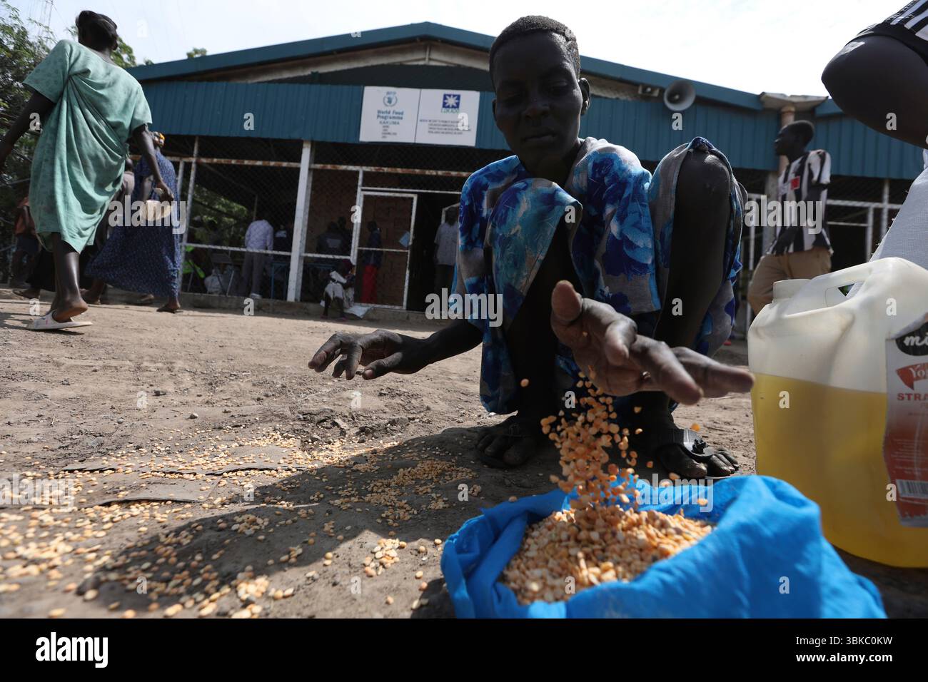 A woman collect split yellow peas as people receive food aid from the ...