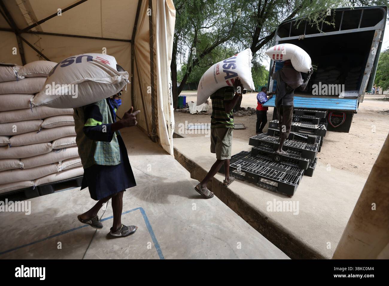 Workers load USAID humanitarian aid into a truck at a World Food ...