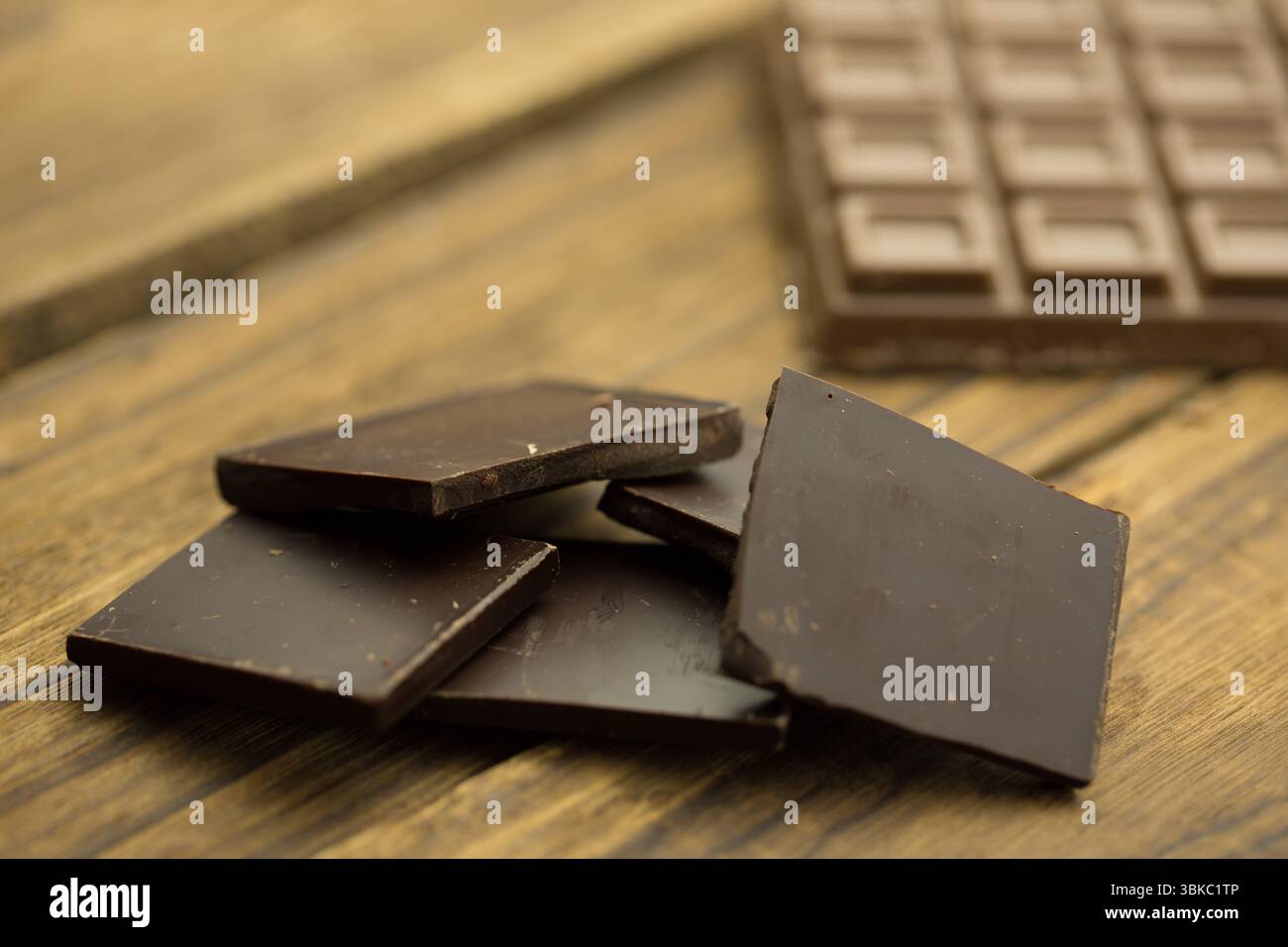 Broken dark chocolate squares are resting on flat design wooden ...