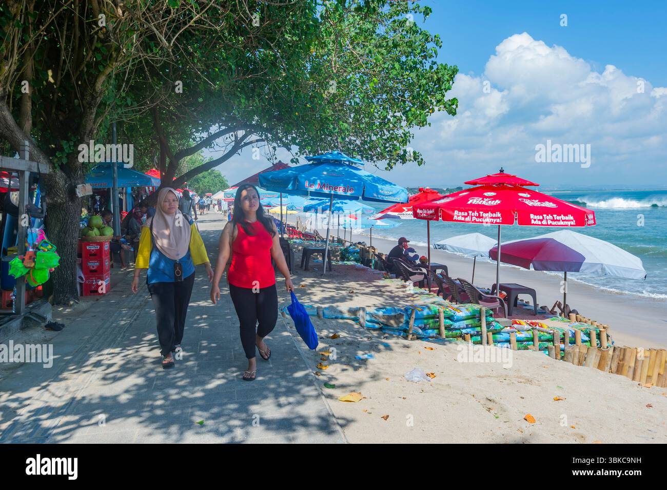 Two ladies strolling along Kuta Beach, a popular tourist destination ...