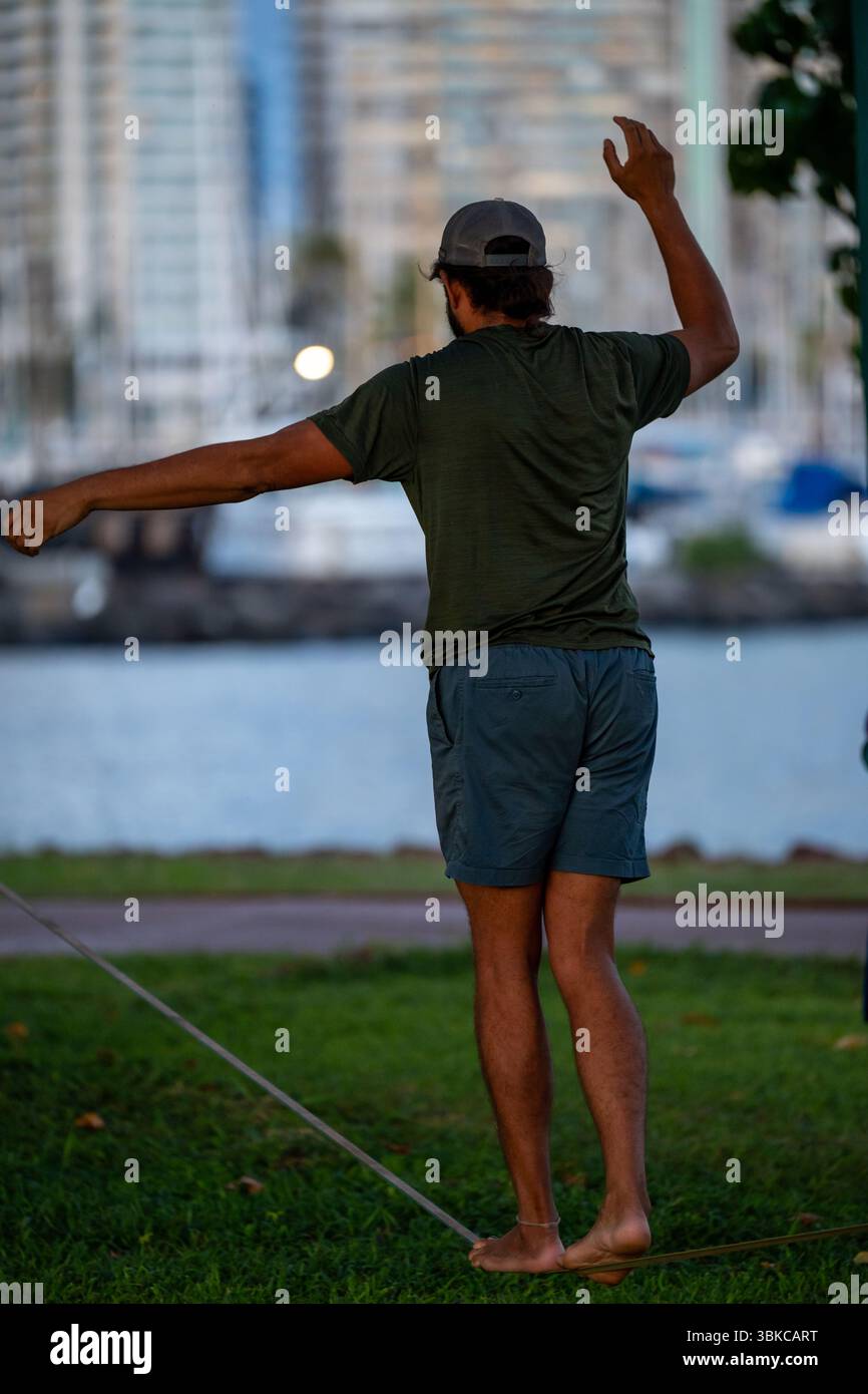 A man balances on a slackline barefoot with arms outstretched for ...