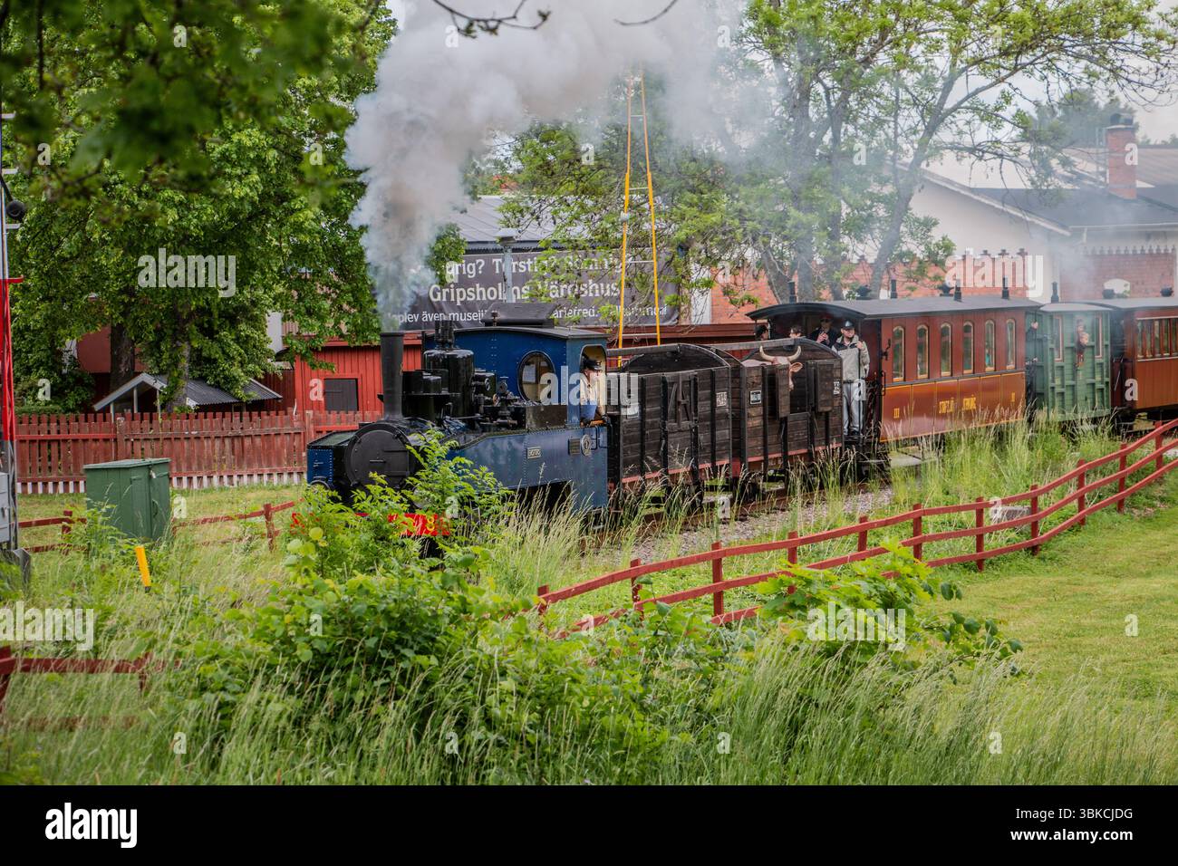 Old steam train on railroad, dark blue and black, driving through the ...