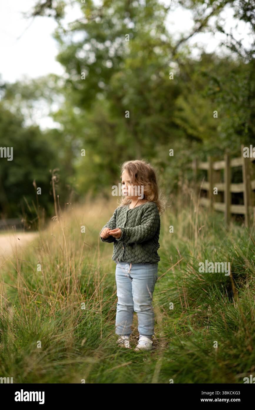 Child girl standing in tall grass on the footpath Stock Photo - Alamy