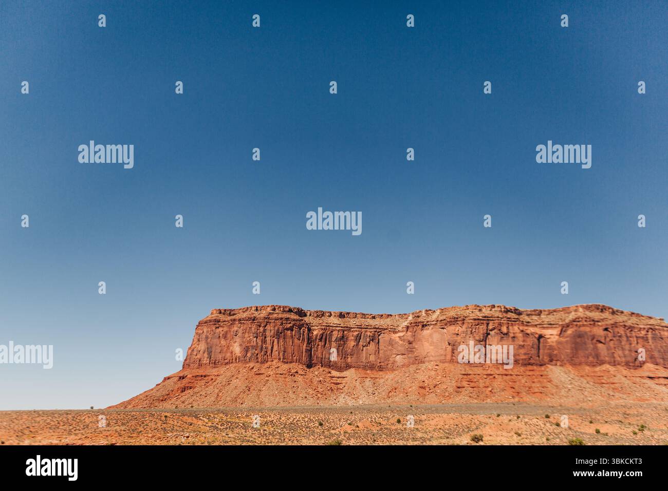 Flat-topped red mesa rises under clear blue sky in Utah desert Stock ...