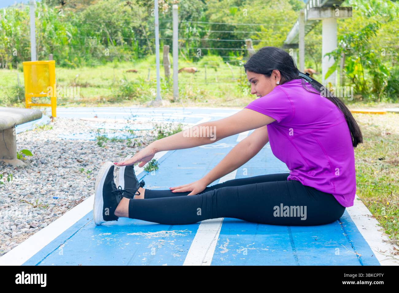 Young Latina Woman Stretching Hamstrings Outdoors on Track Stock Photo ...