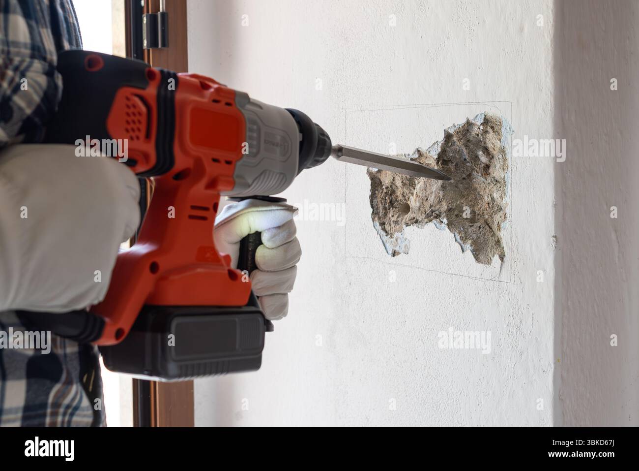 Carpenter electrician with demolition hammer prepares the cavity in the ...