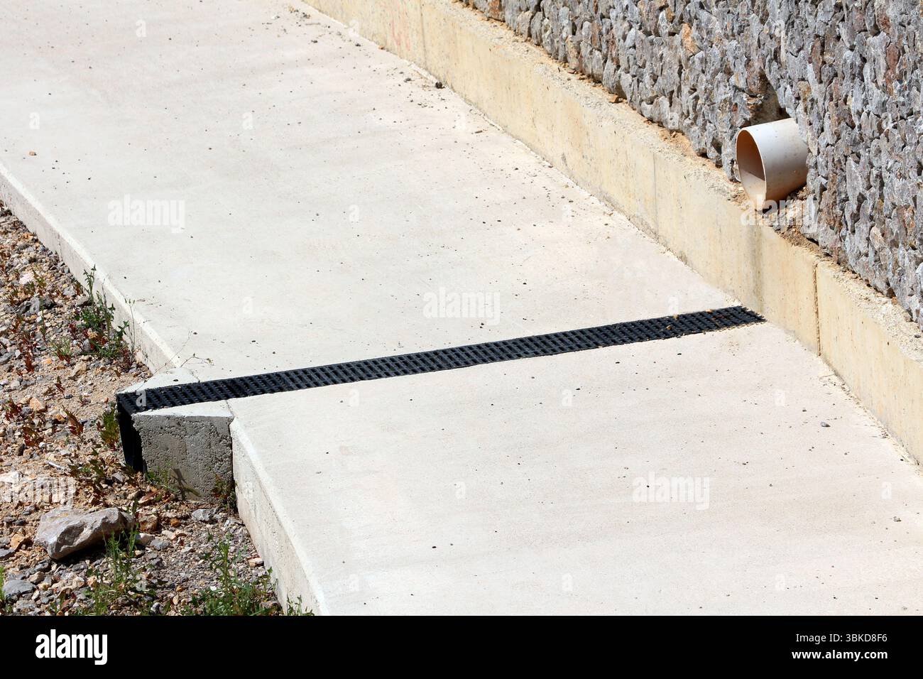 Light concrete drainage channel with a white outflow pipe and black ...
