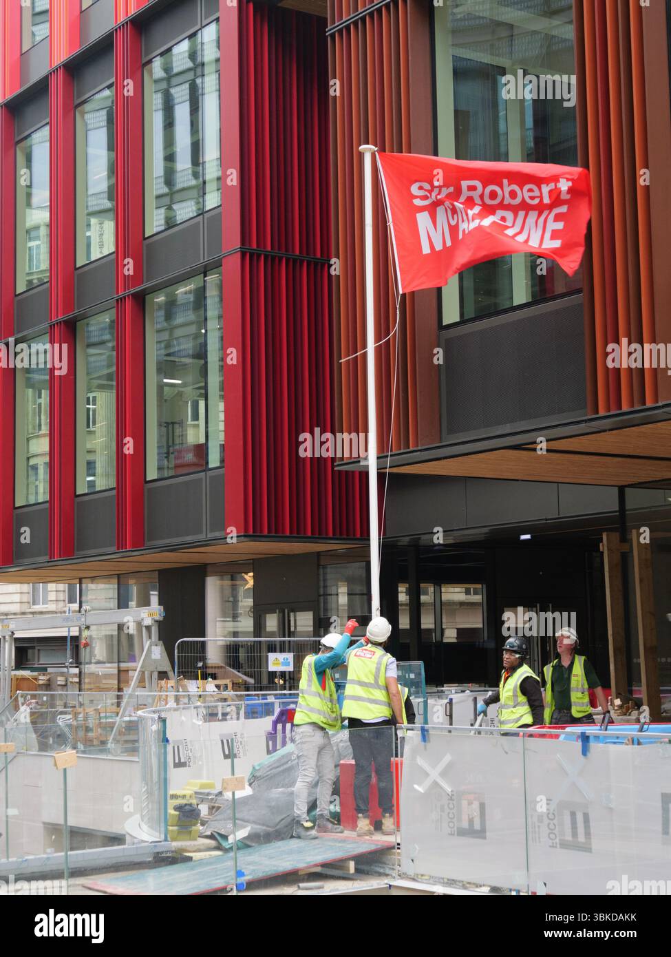 Construction workers for Sir Robert McAlpine raise a branded flag at a ...