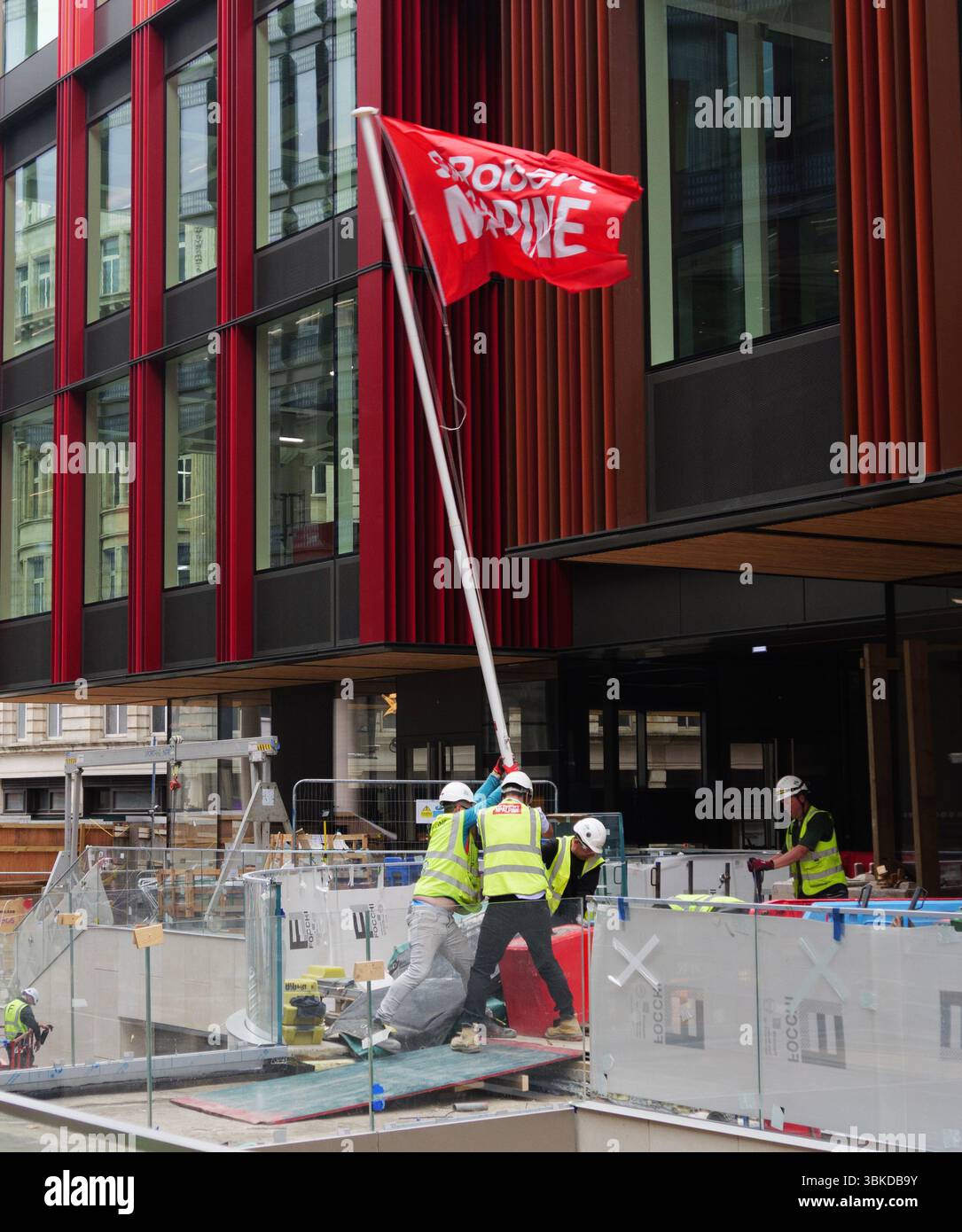 Construction workers for Sir Robert McAlpine raise a branded flag at a ...