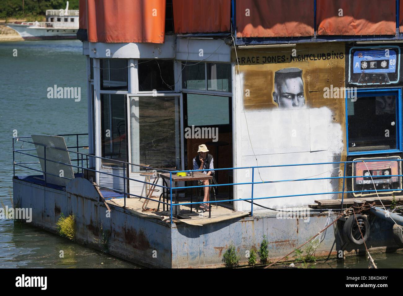 A man rests at a closed raft restaurant on the banks of Sava river ...