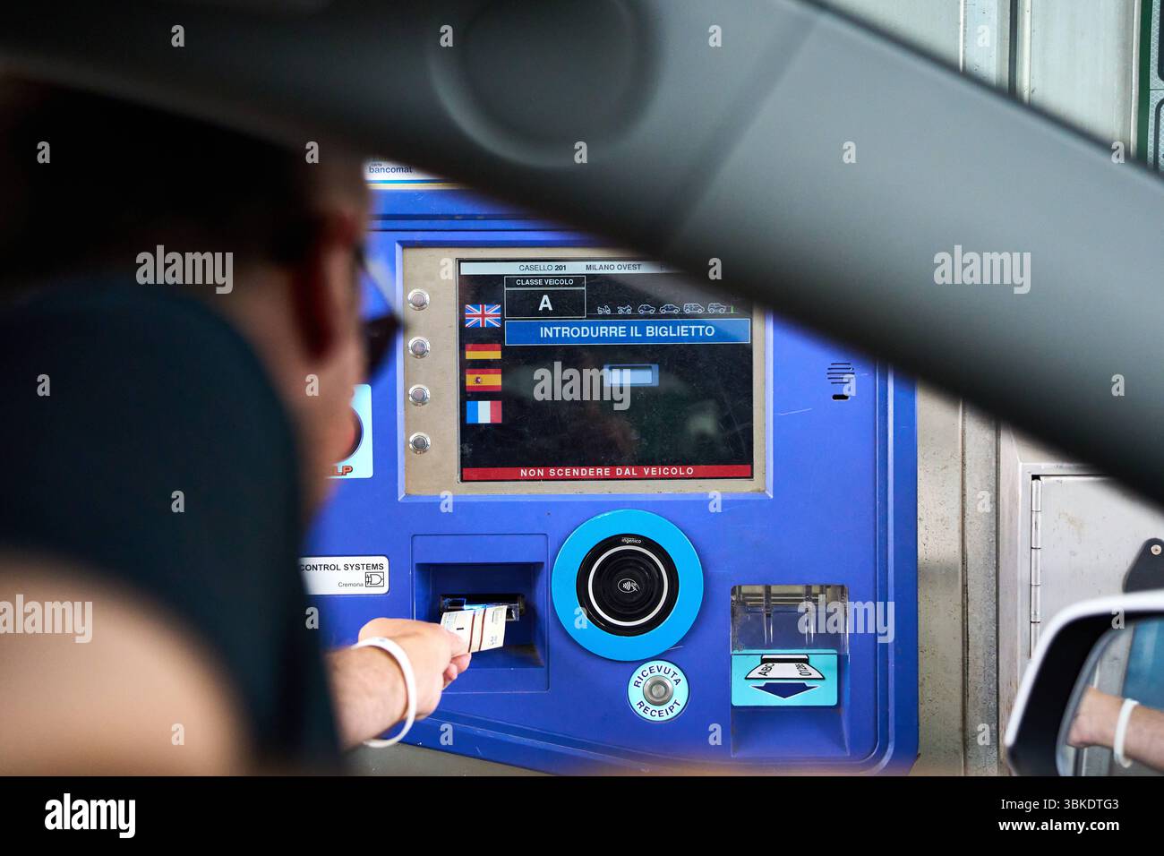 Italy - June 15, 2025: Driver pulls ticket into a machine at a toll ...