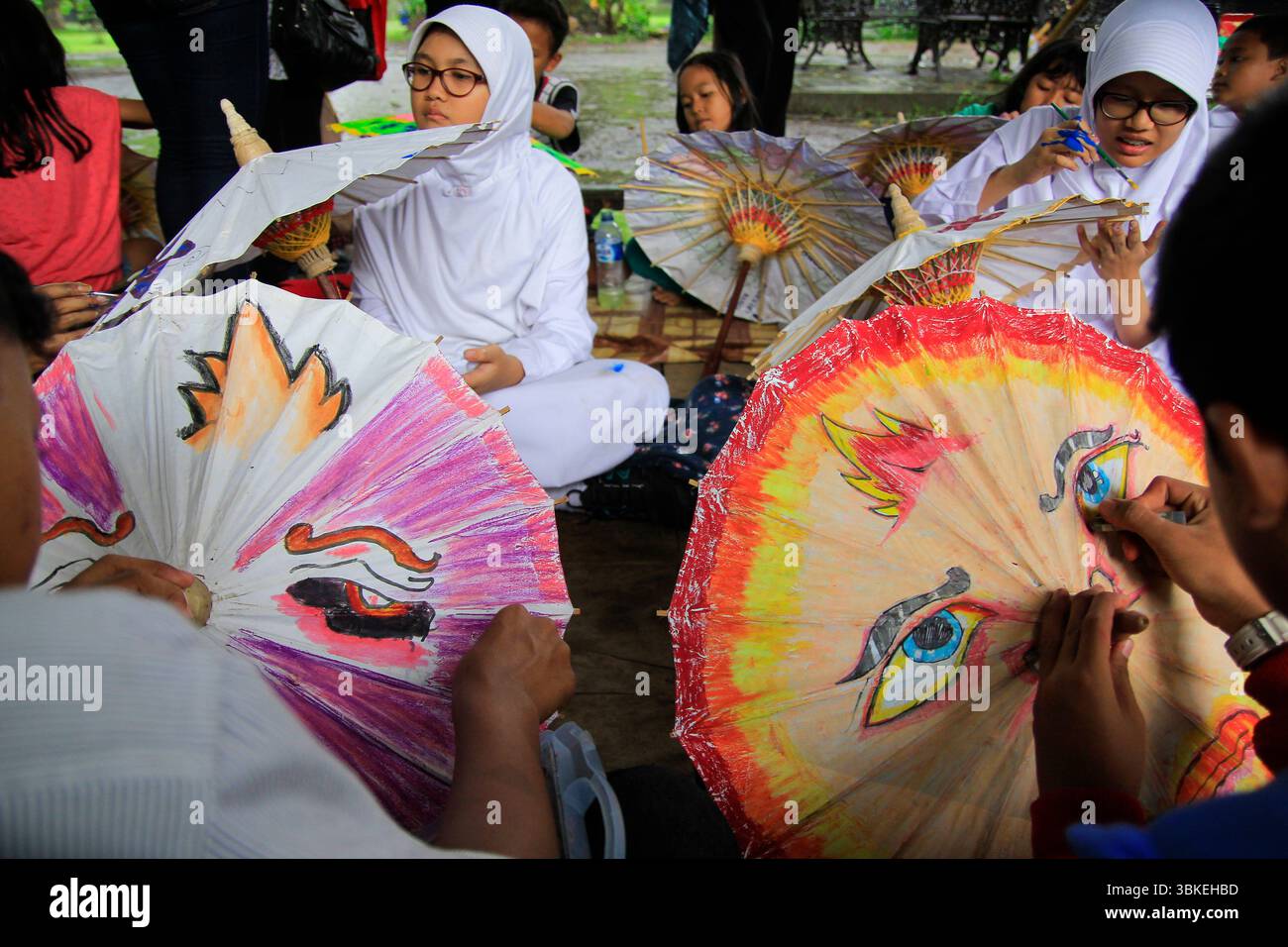 Girl participant concentrated on painting the Juwiring paper umbrella ...