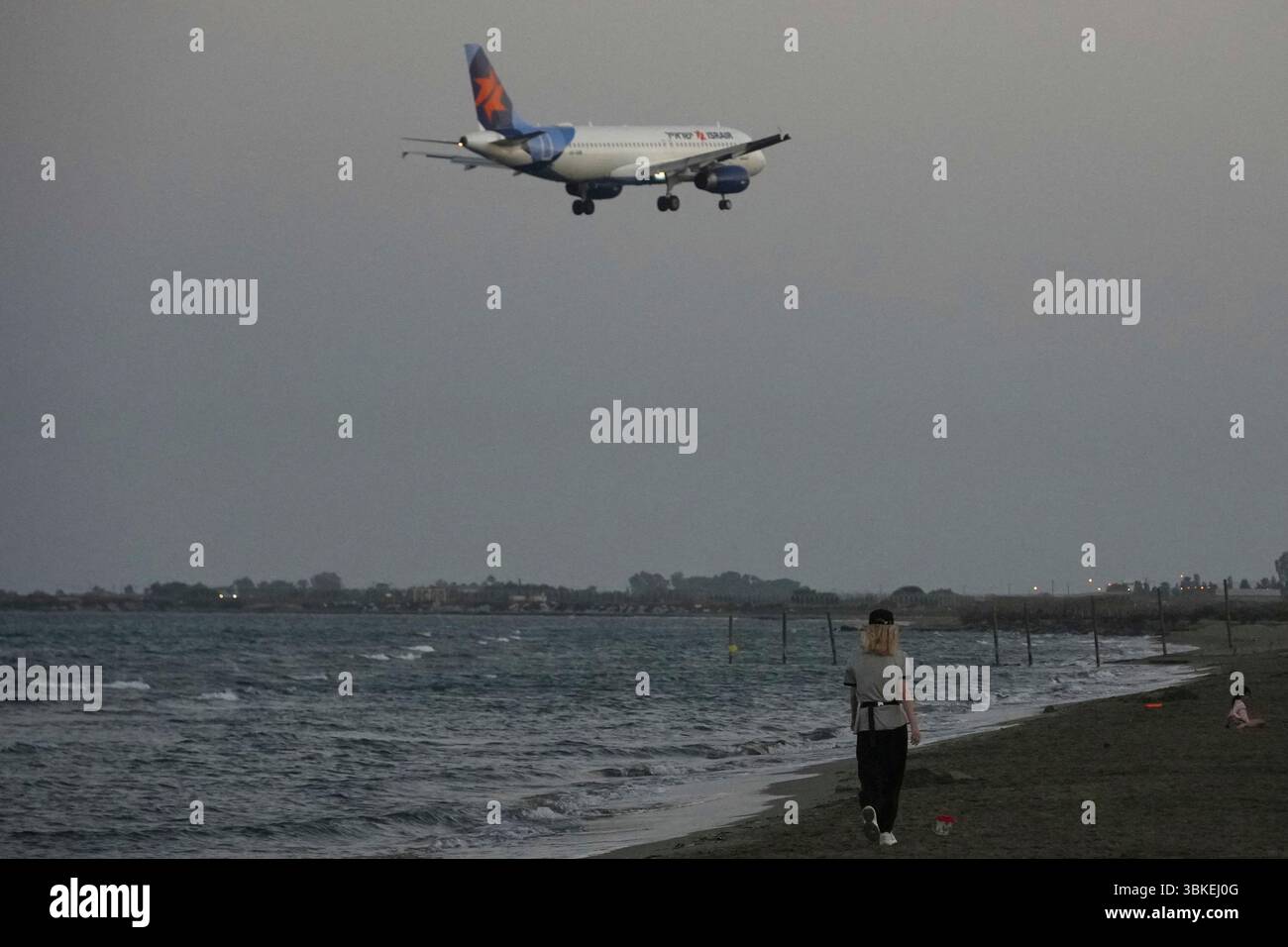 A woman walks on the beach as an Israeli aircraft prepares to land at ...