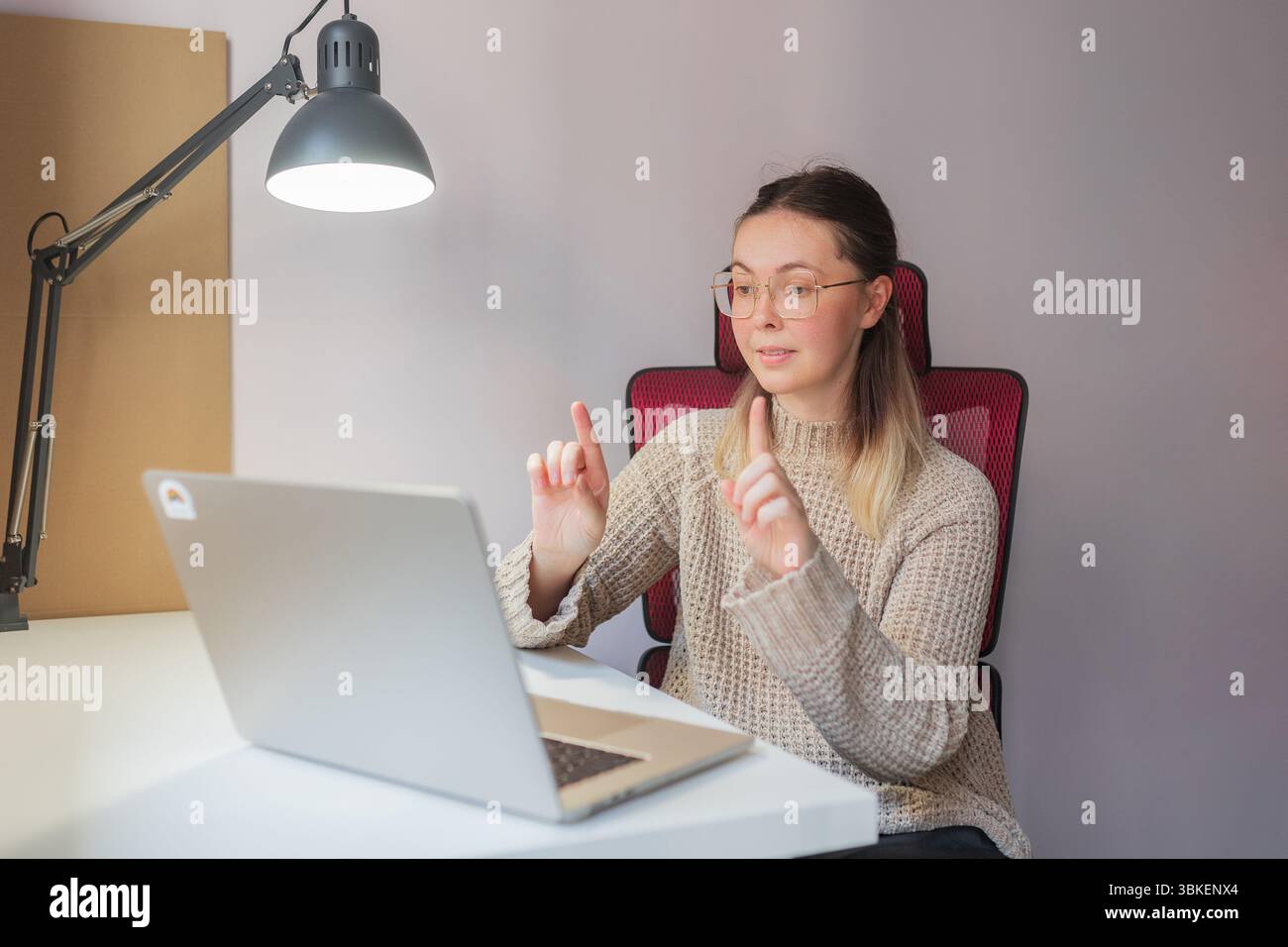Woman raising finger, appearing to explain something during video call ...