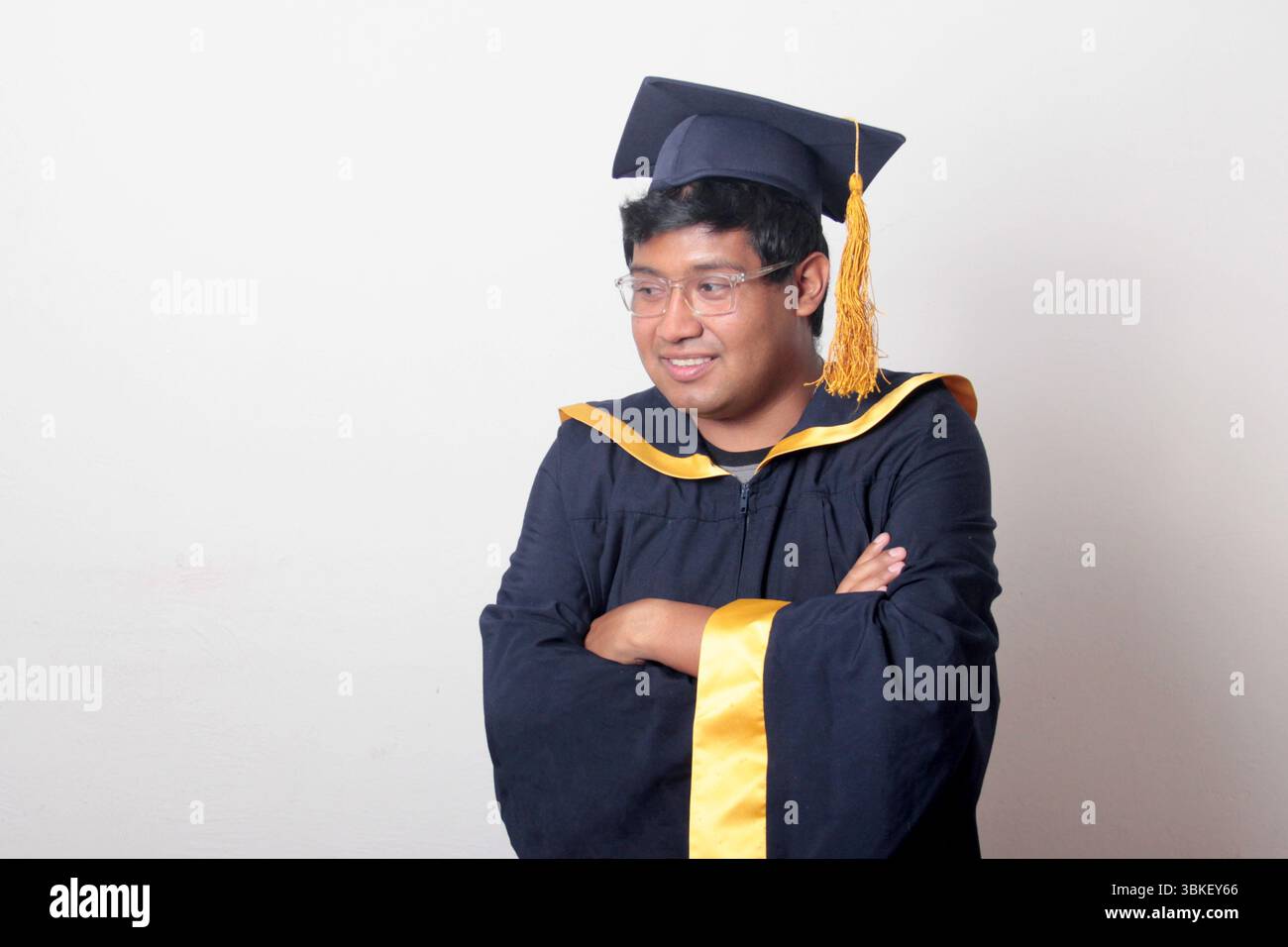 30-year-old dark-skinned Latino man with glasses wears a cap and gown ...