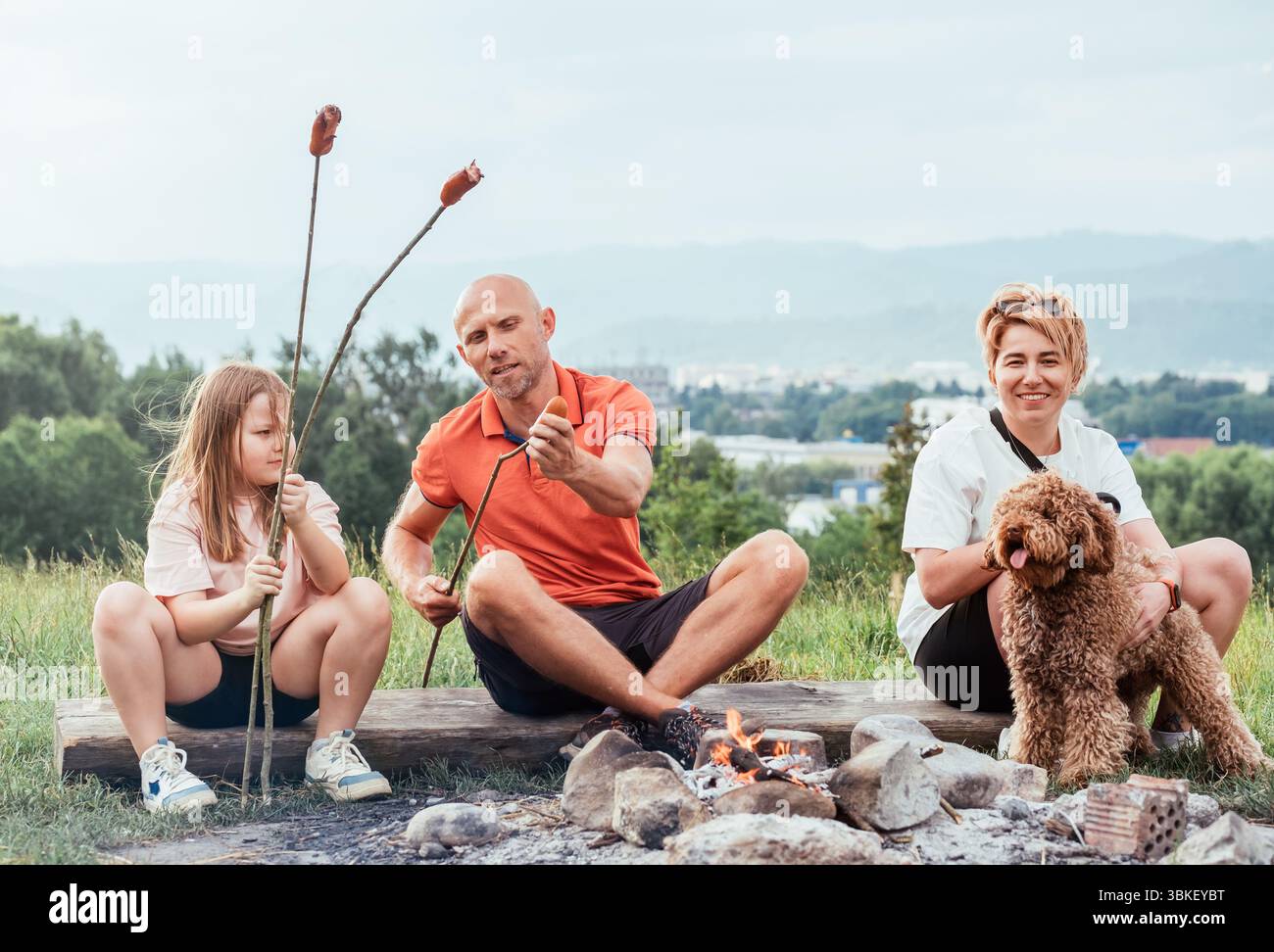 Father showing daughter how to put sausage on barbecue stick while ...