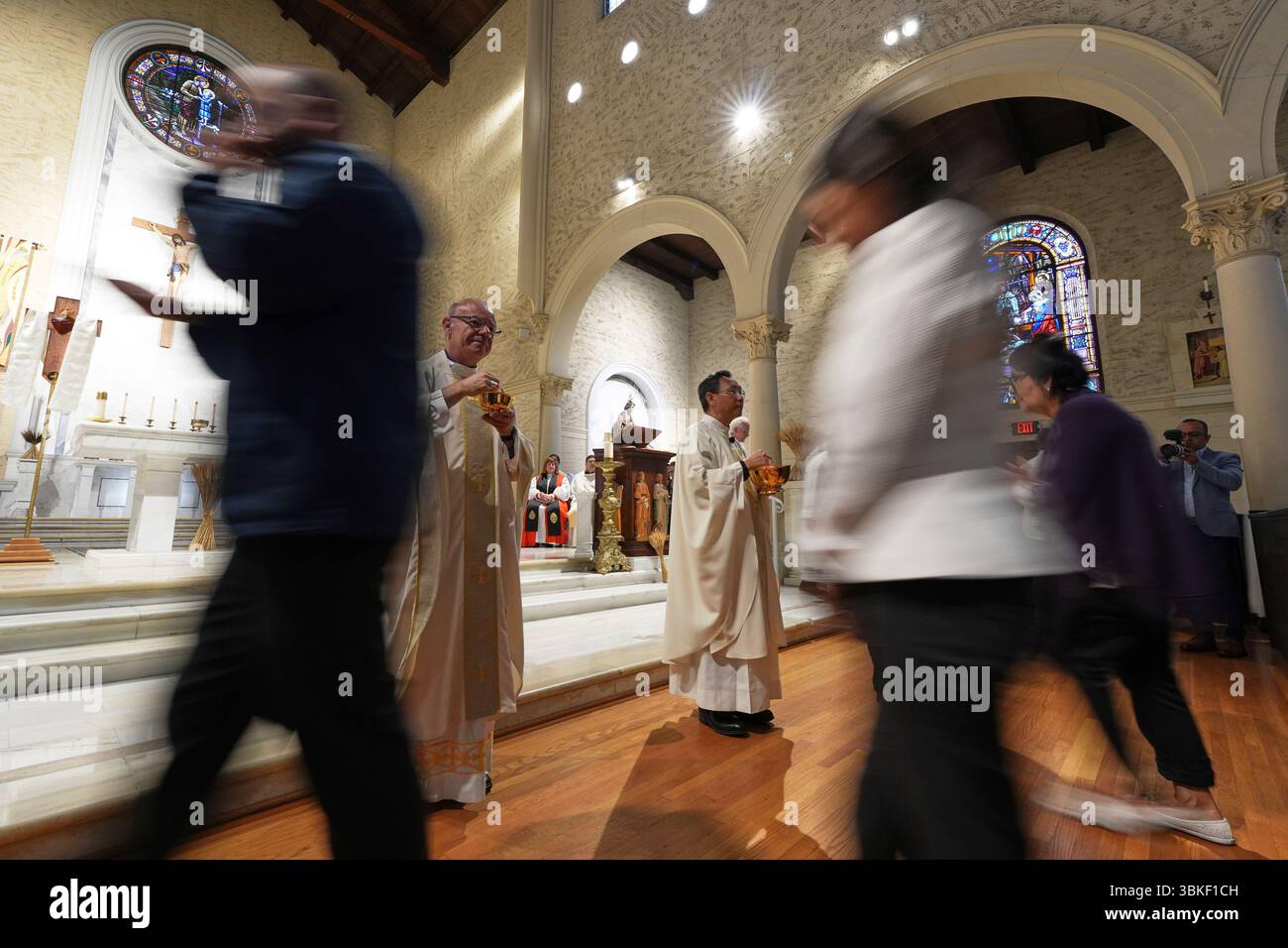 Bishop Michael Pham, center right, performs communion during Mass ...