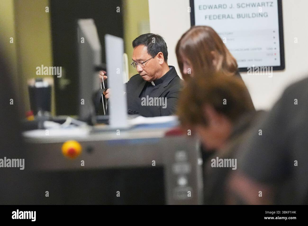 Bishop Micheal Pham, center, picks up personal items from a scanner as ...