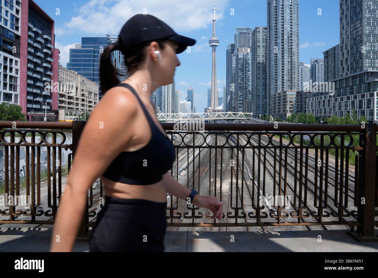 A woman passes by city skyline in Toronto, Canada, Friday, June 2025 ...