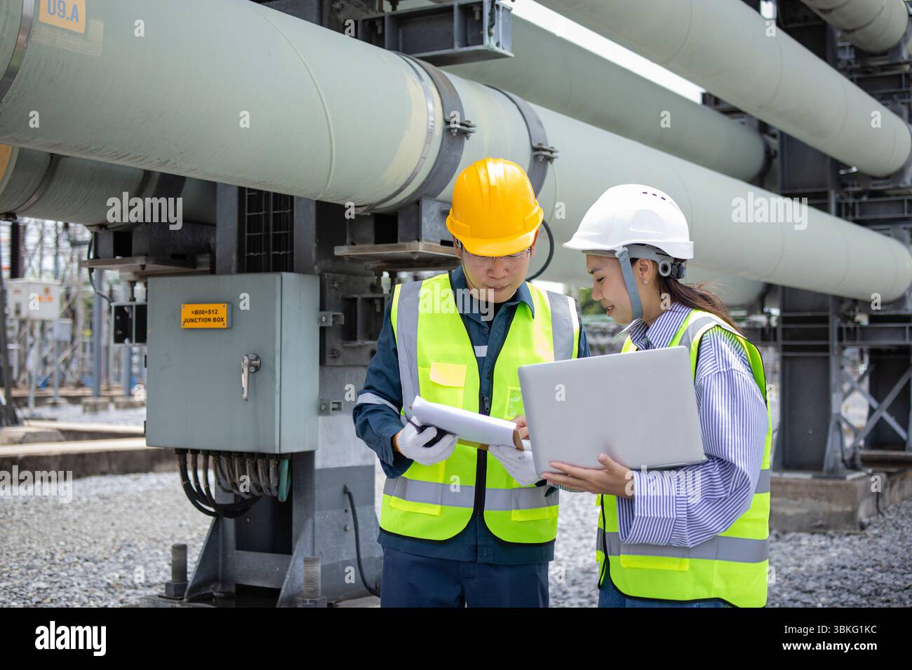 An engineer working at power station reviewing documents and laptop ...