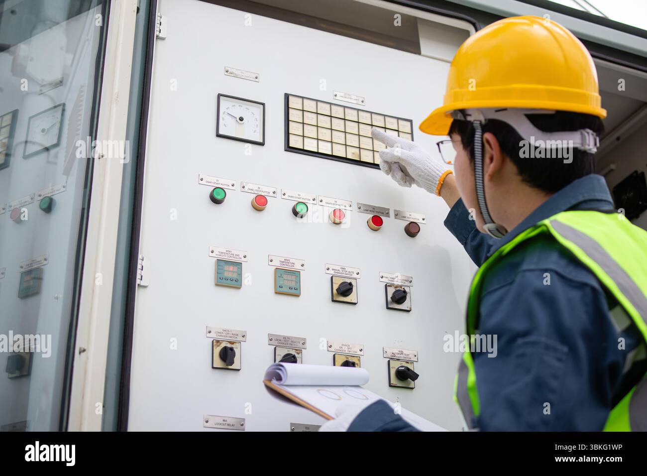 An engineer wearing yellow helmet performs inspection on transformer ...