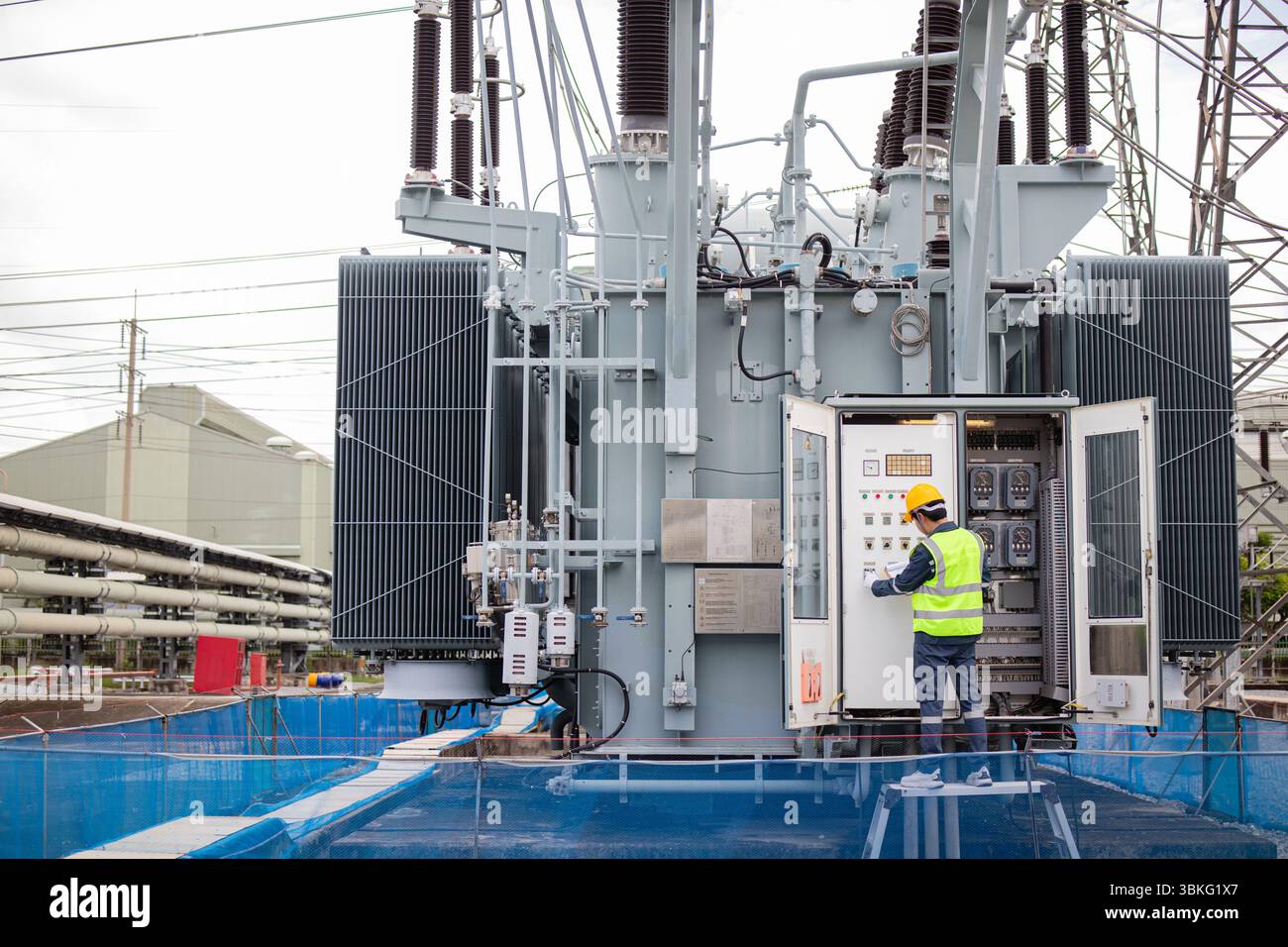 An engineer performs inspection on large transformer at outdoor ...