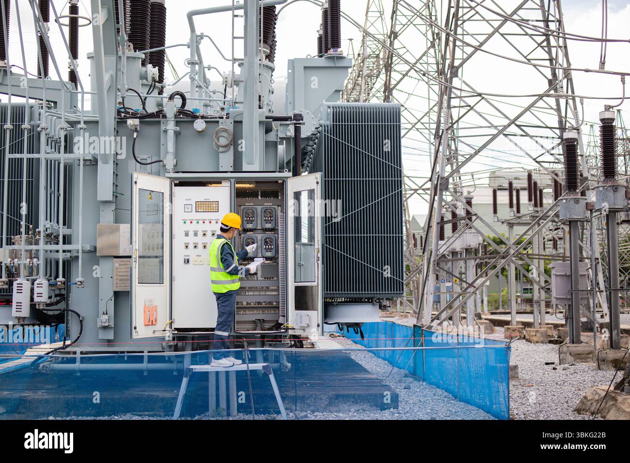 An engineer performs inspection on large transformer at electrical ...