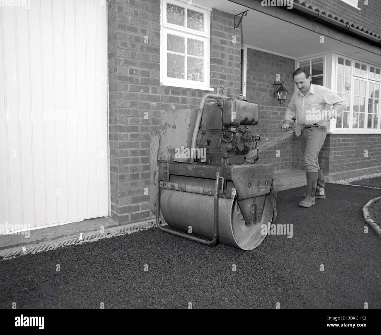 1980s, house, new driveway, man with roller, rolling tarmac Stock Photo ...