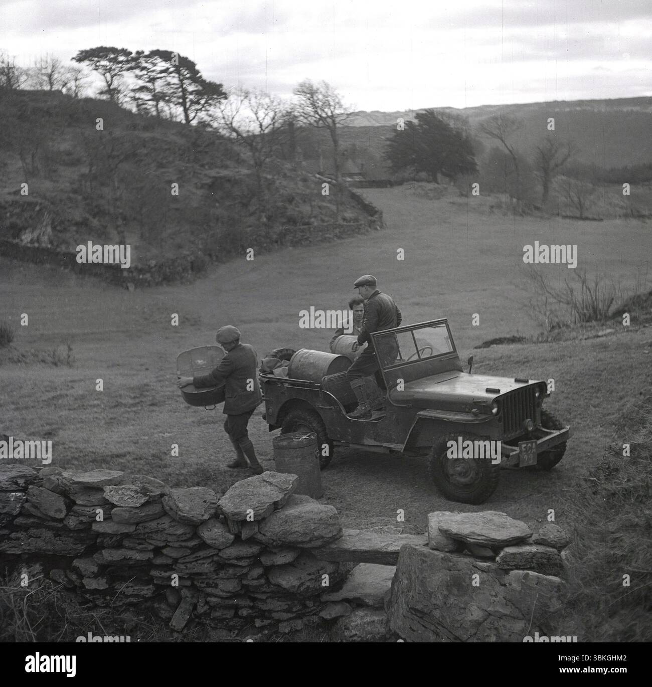 1950s, historical, farmers outside in a high lying field, unloading ...
