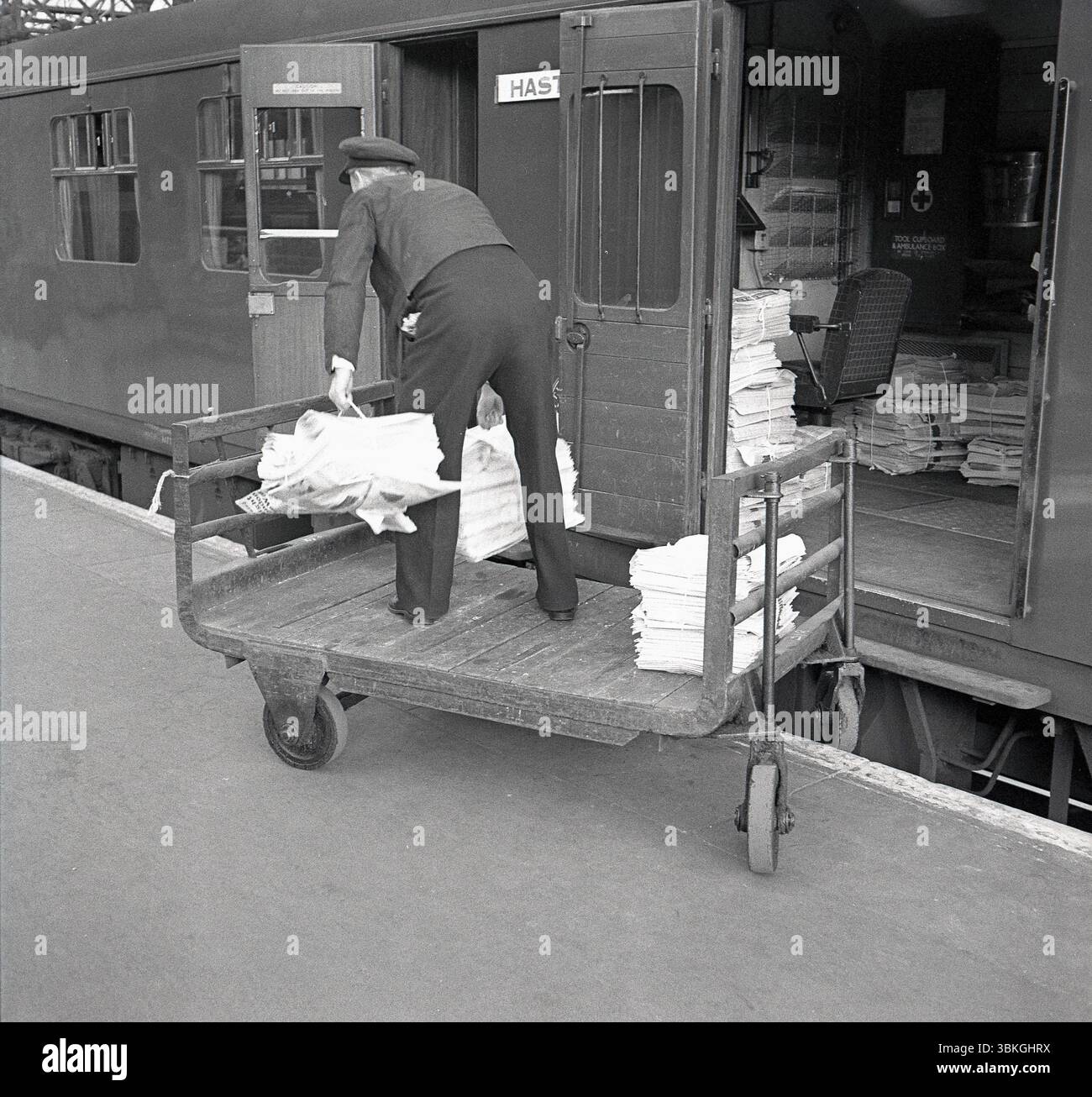 1960s, historical, a uniformed British Rail guard standing on a wheeled ...
