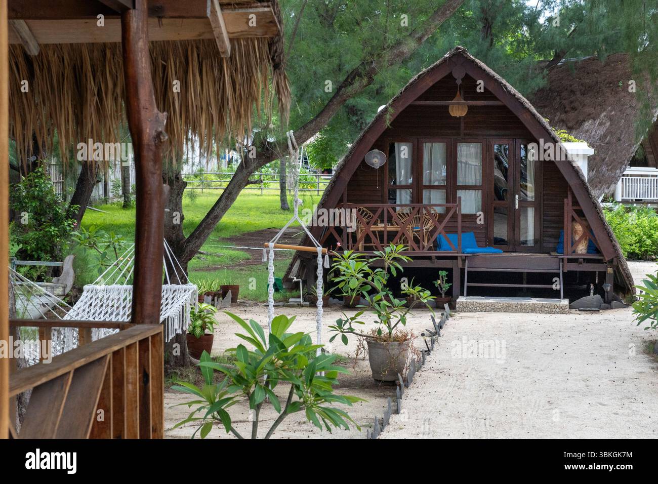 Small hut with a porch and a swing hanging from a tree. The hut is ...