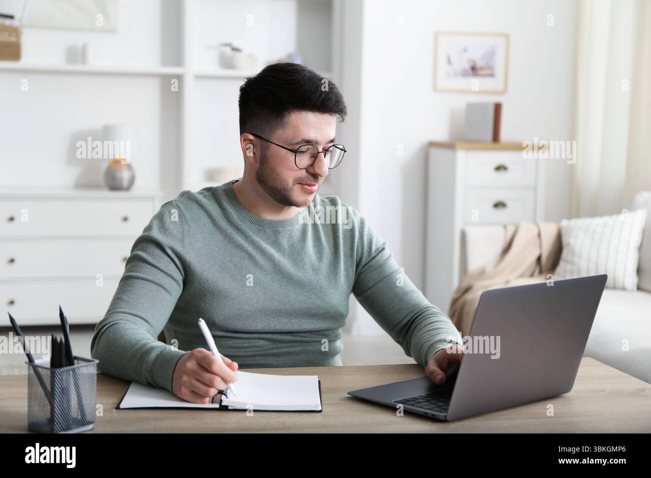 Man taking notes during online lesson at desk indoors. Self-study Stock ...