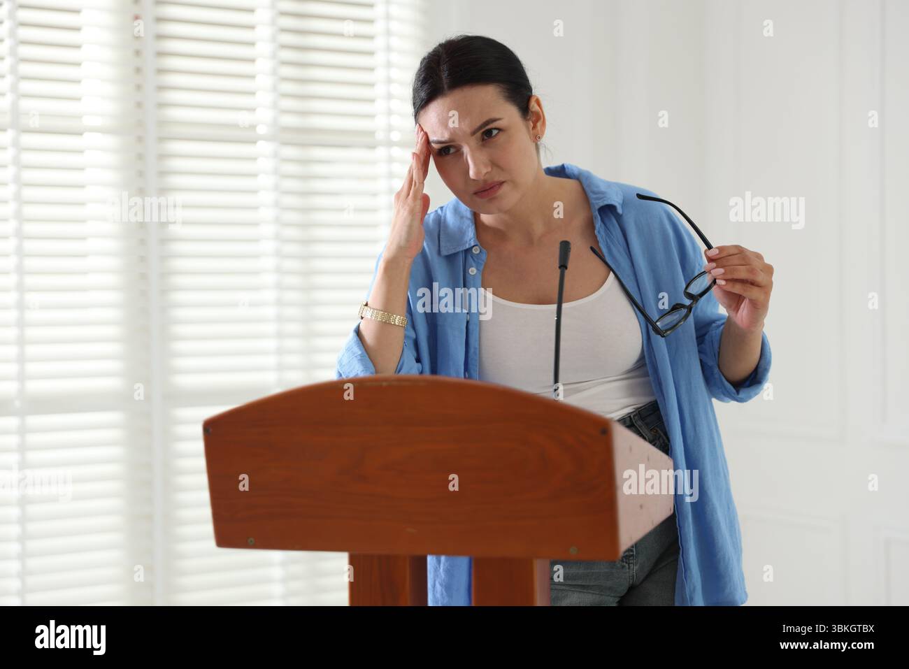 Fear of public speaking. Nervous woman with microphone at lectern ...