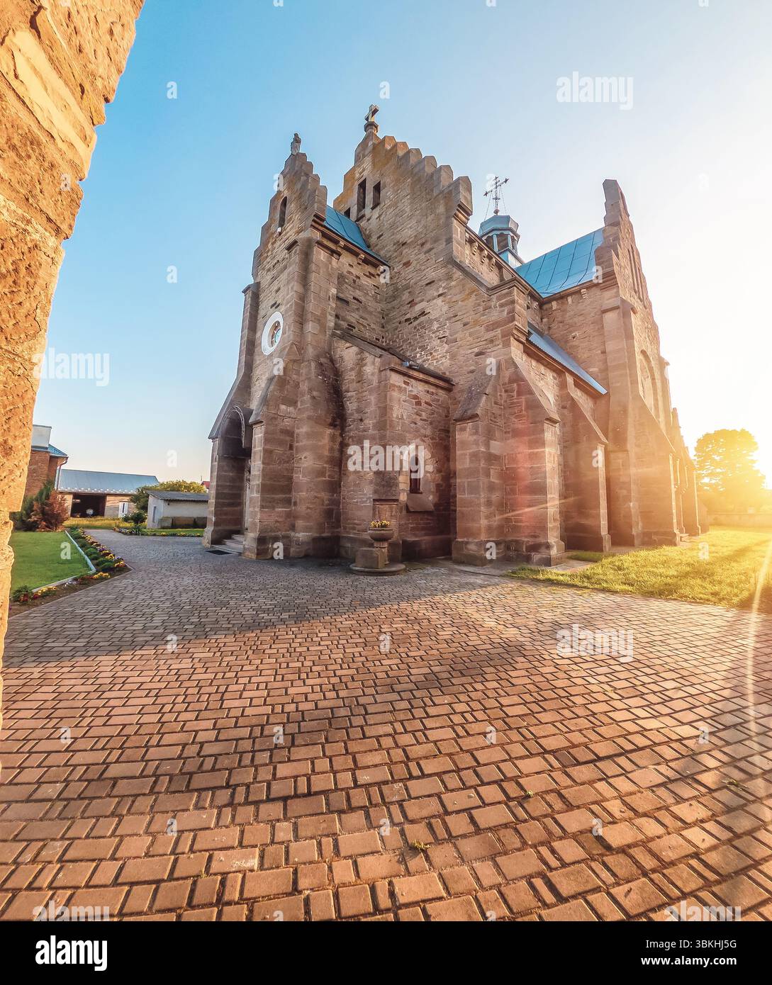 View through arched gate to restored stone church with cobblestones in ...