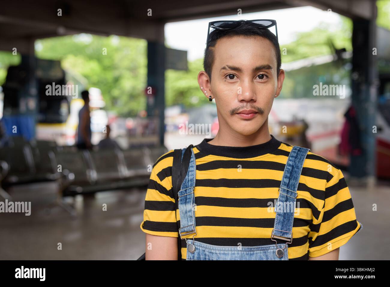 Cute nonbinary genderfluid young Asian gay tourist man in bus terminal ...