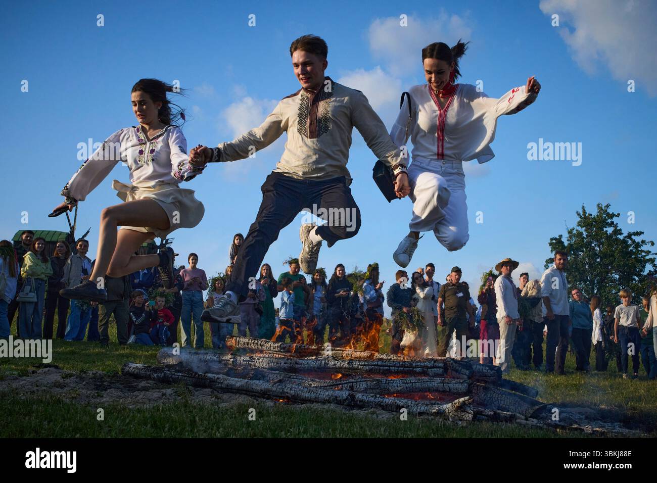 People jump over bonfire during a traditional midsummer celebration in ...