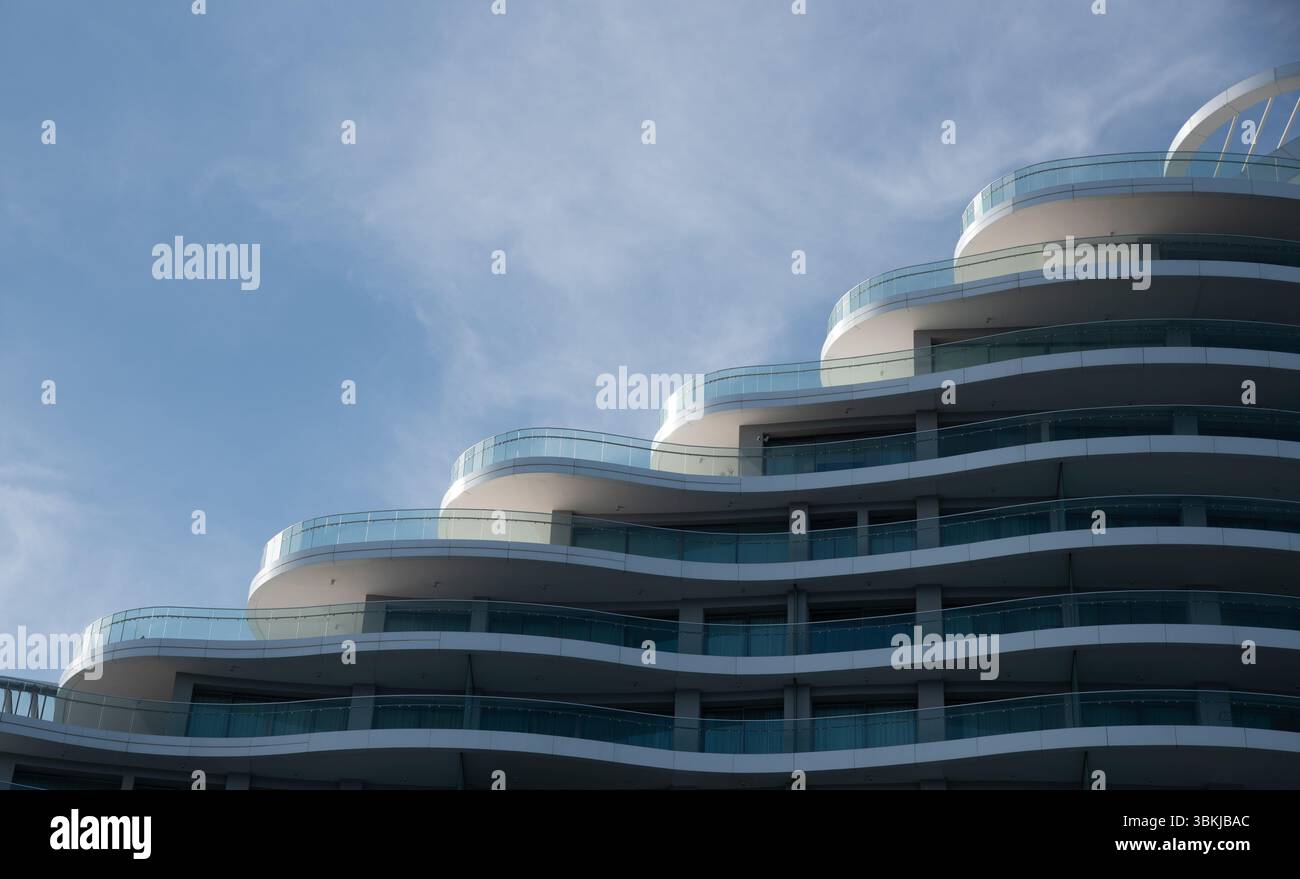 Glass balconies wrapping around a modern residential building create a ...