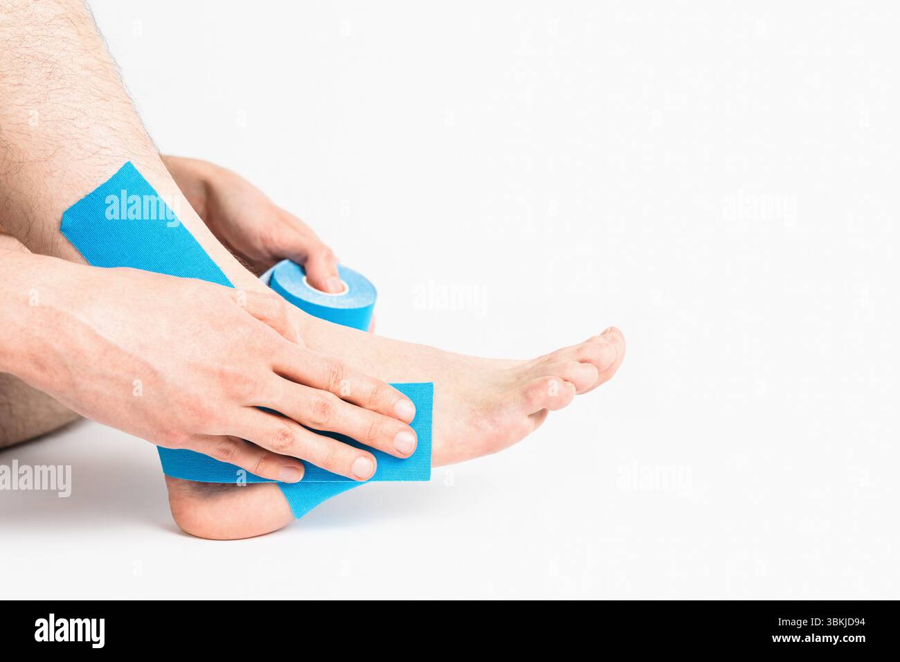 Hands apply elastic kinesiology tape along the heel and arch of the ...
