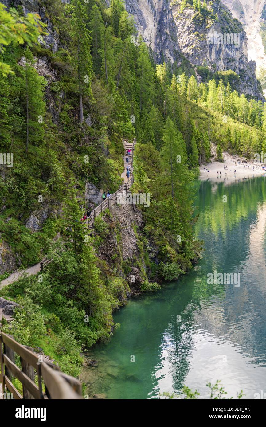 A narrow path winds along a steep slope with a view of an emerald green ...