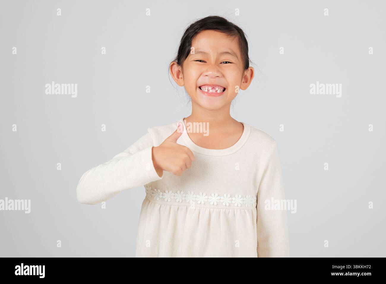 Smiling child with a missing tooth gives a thumbs up Stock Photo - Alamy