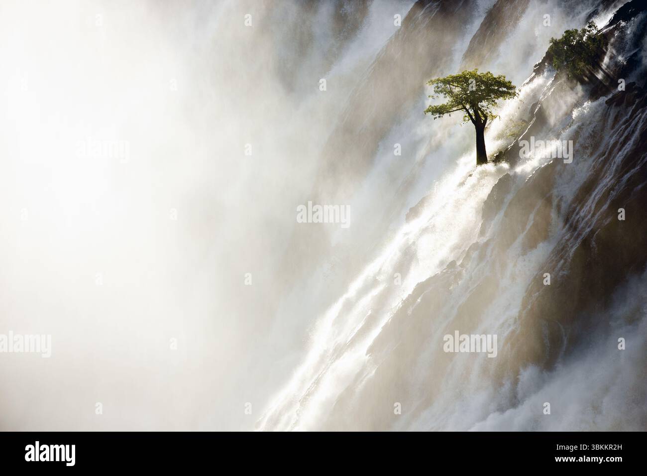 The bright light rays of a setting sun beams down into Ruacana Falls on ...