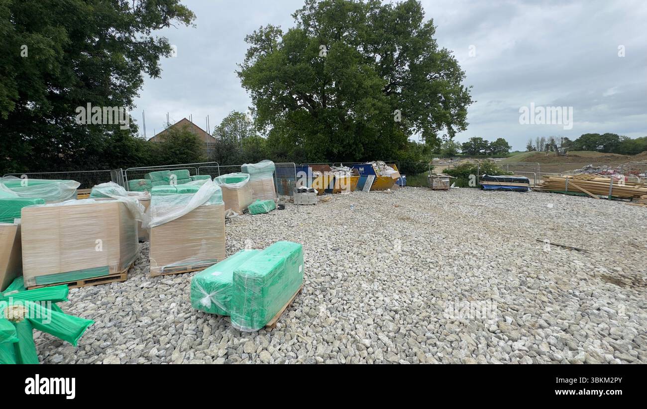 Construction site with gravel ground, stacked materials, waste bins ...
