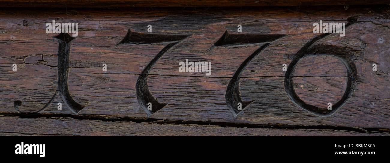 Carved numbers 1776 marked on worn wood, representing historical ...