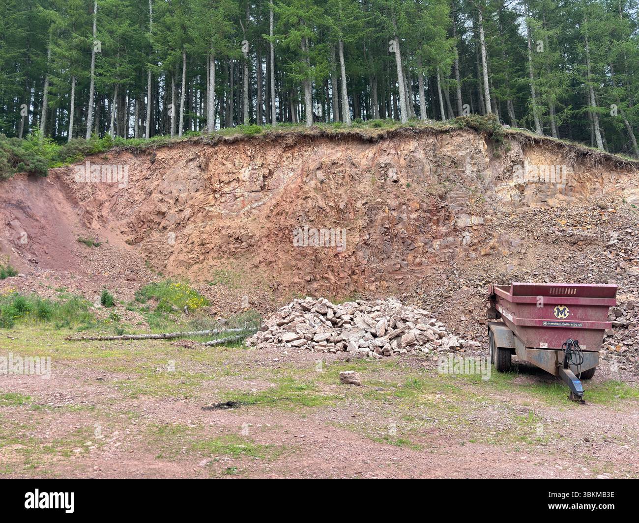 Agricultural trailer parked beside a rock face at a small quarry site ...