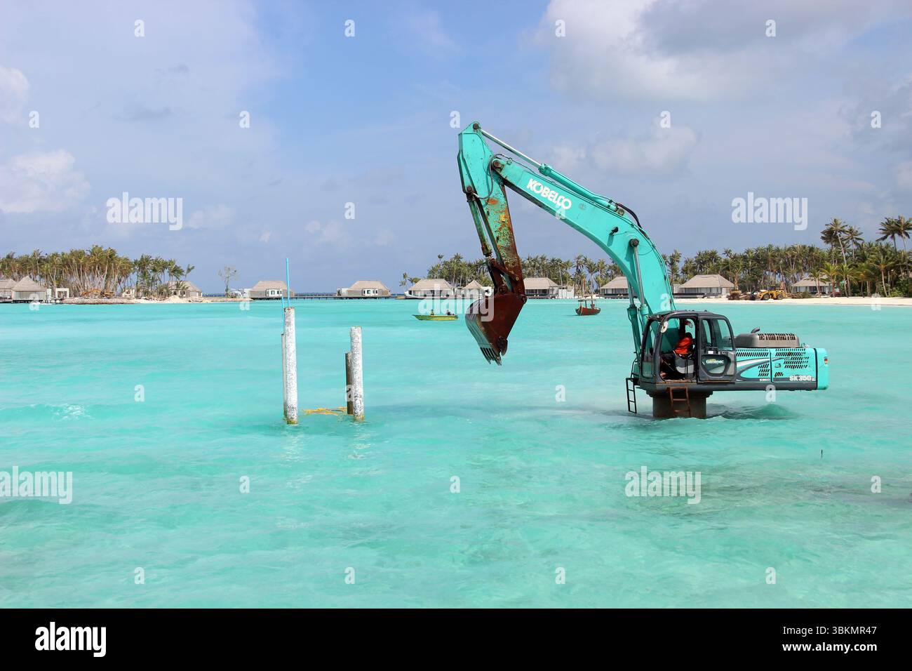 An excavator in the tropical sea of the Maldives is working on the ...