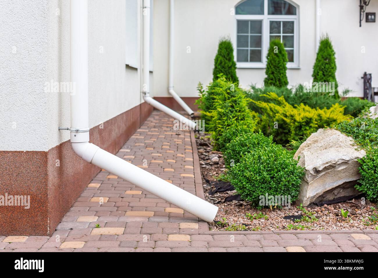 White PVC downspouts channel rainwater away from a house foundation ...