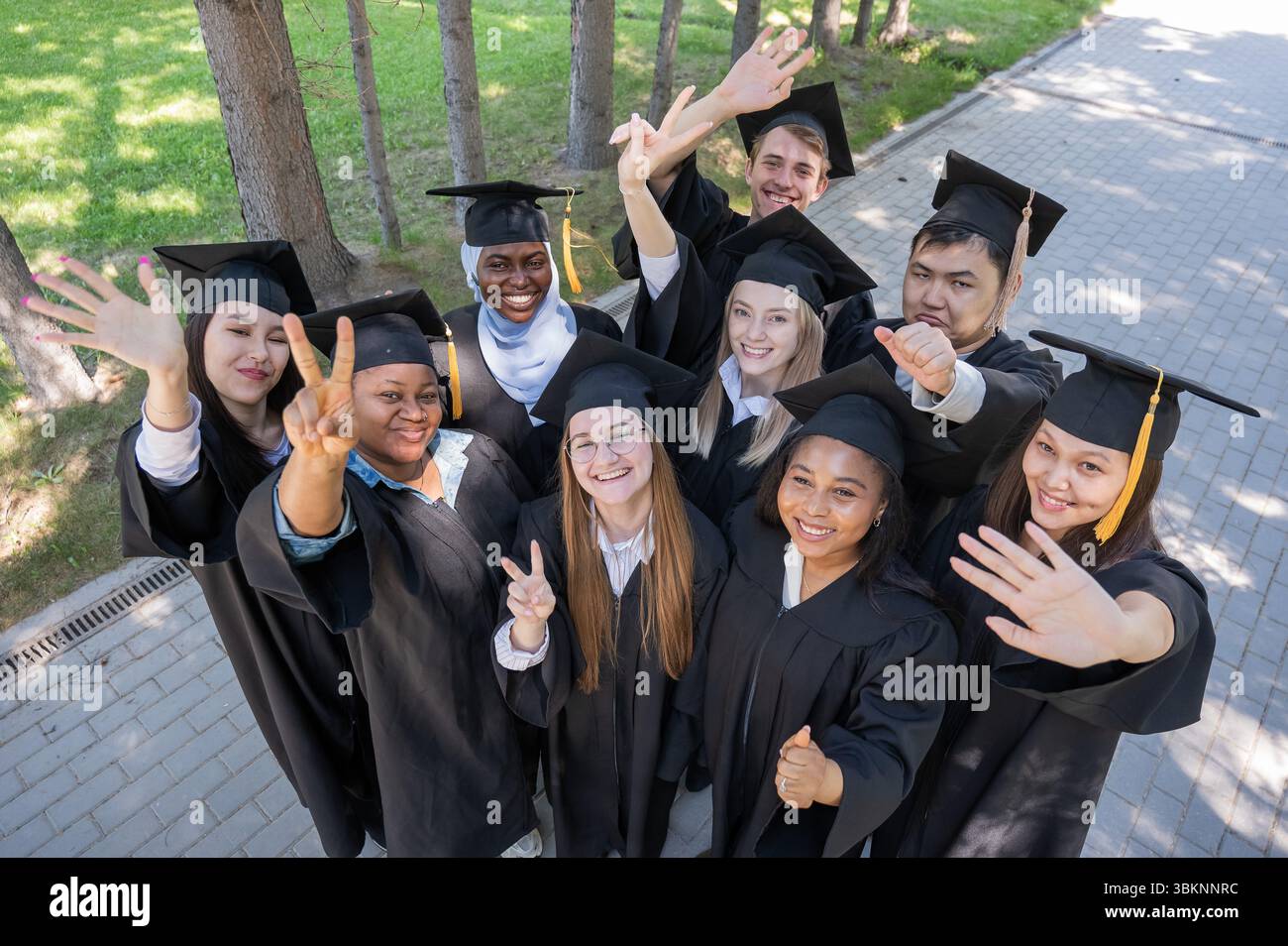 Students of different nationalities in graduation gowns wave their ...