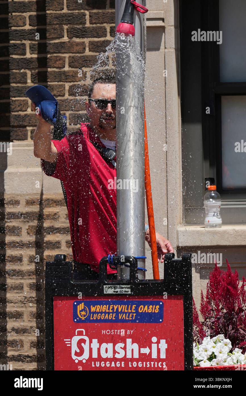 A Chicago Cubs security guard cools off under a sprinkler provided by a ...